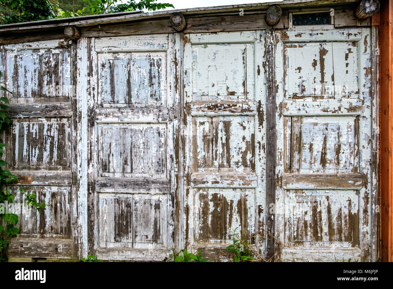Old wooden wall made of shabby door panels in countryside. Front view ...