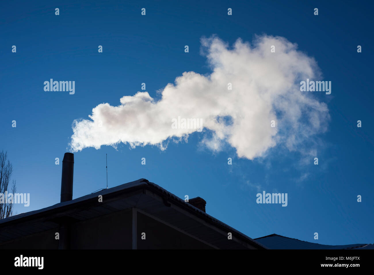 smoke coming out of house chimney. blue sky background Stock Photo - Alamy