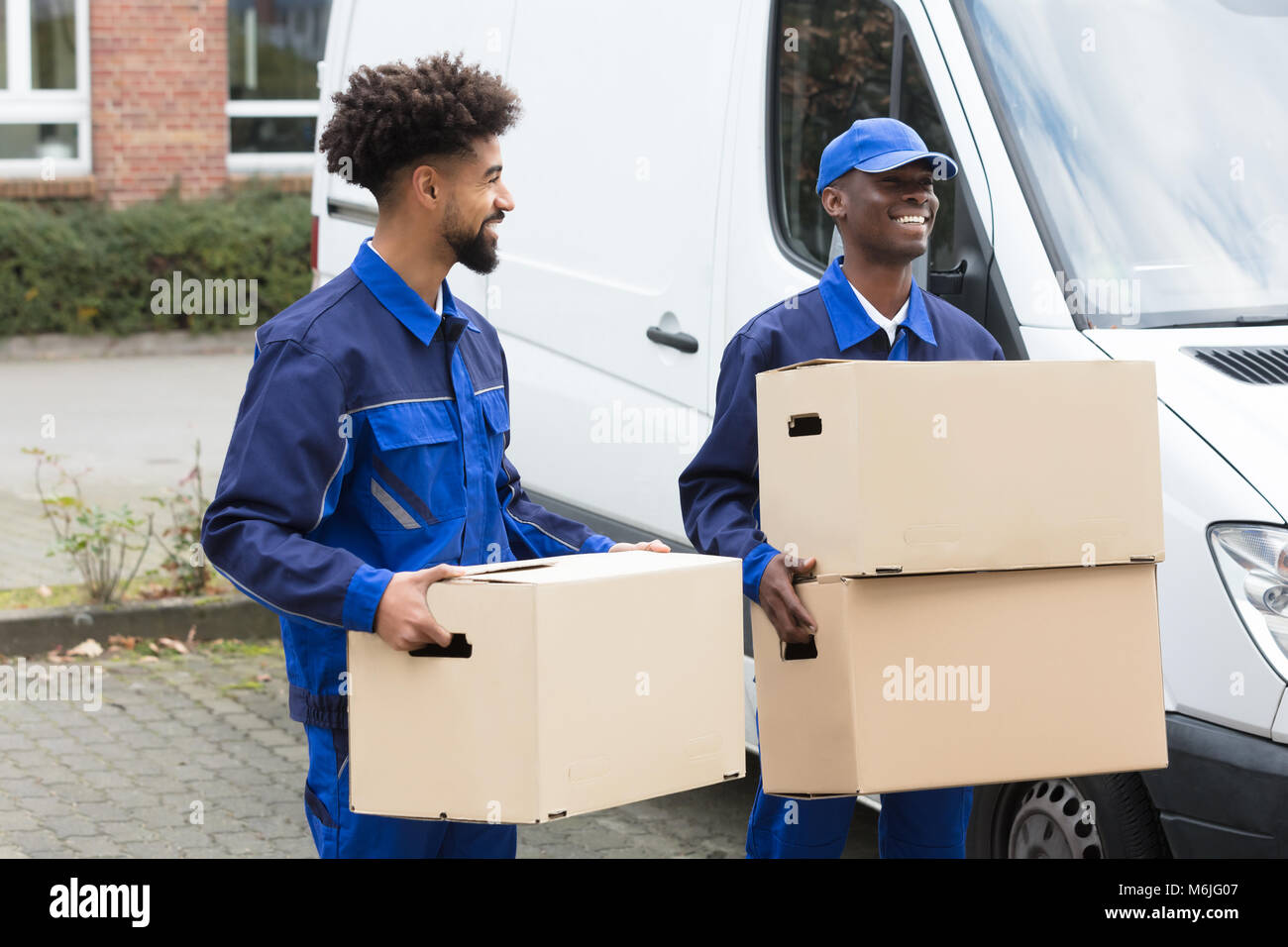 Close-up Of Two Delivery Men Holding The Cardboard Boxes Stock Photo ...