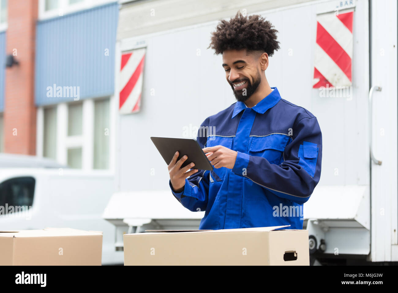 Smiling Delivery Man Standing Near The Van Checking His Order On ...