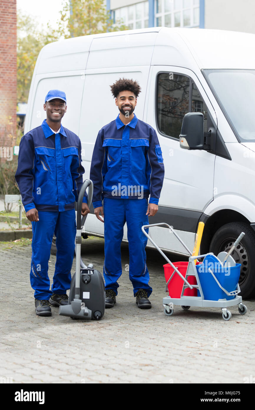 Portrait Of Two Happy Male Janitor Standing With Cleaning Equipment ...