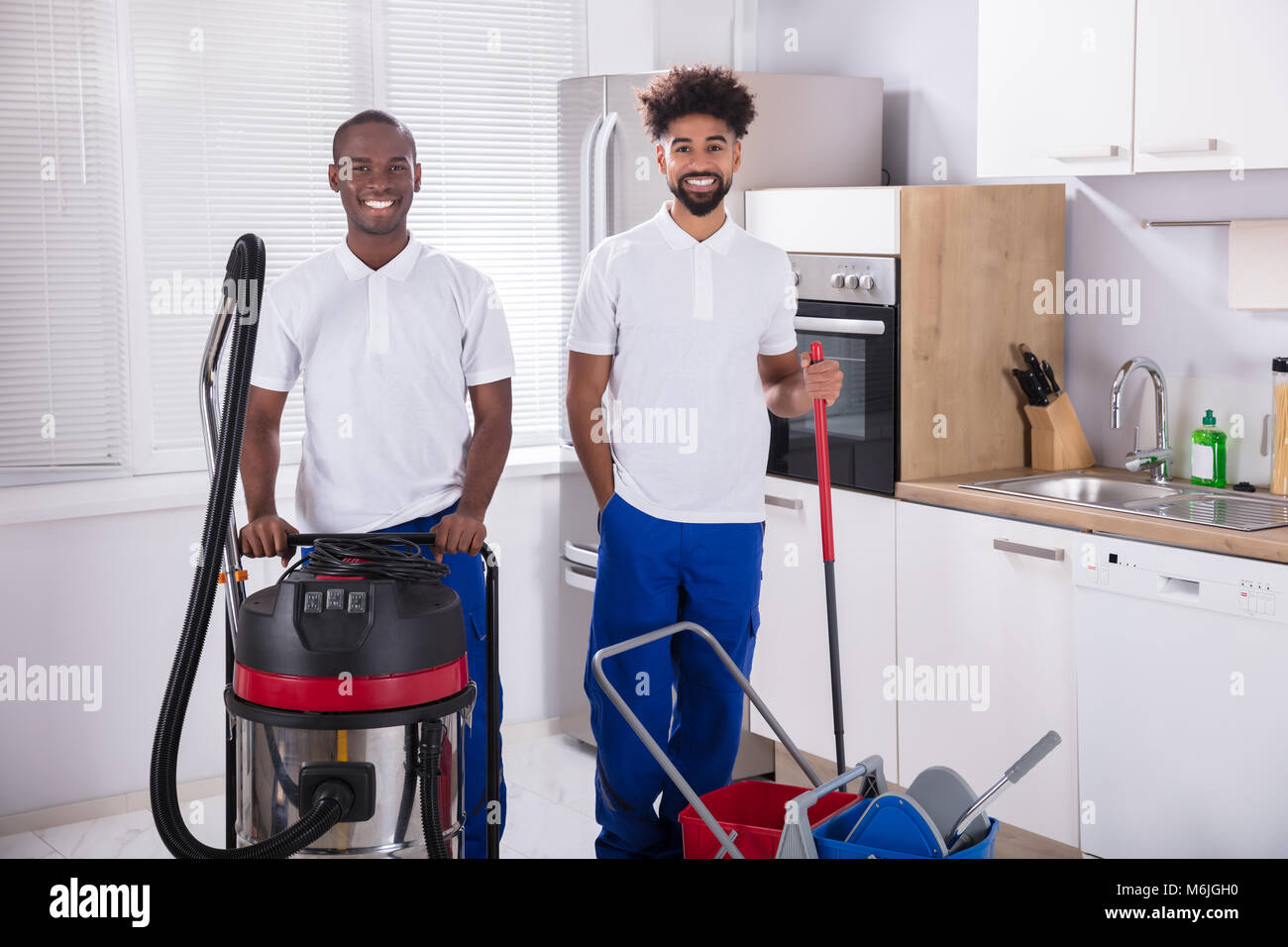 Portrait Of Two Young Happy Male Janitor Standing With Cleaning ...