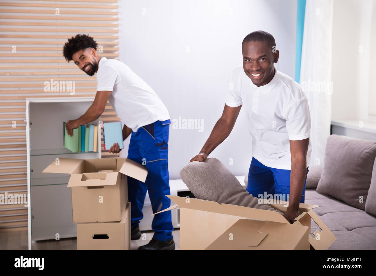 Smiling Young Movers Unpacking The Cardboard Boxes In The Home Stock ...