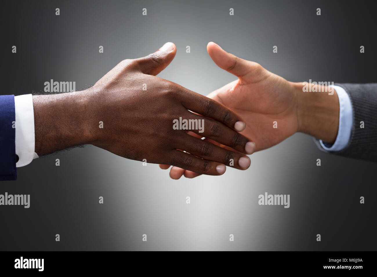 Close-up Of Two People Shaking Hands On Gray Background Stock Photo - Alamy