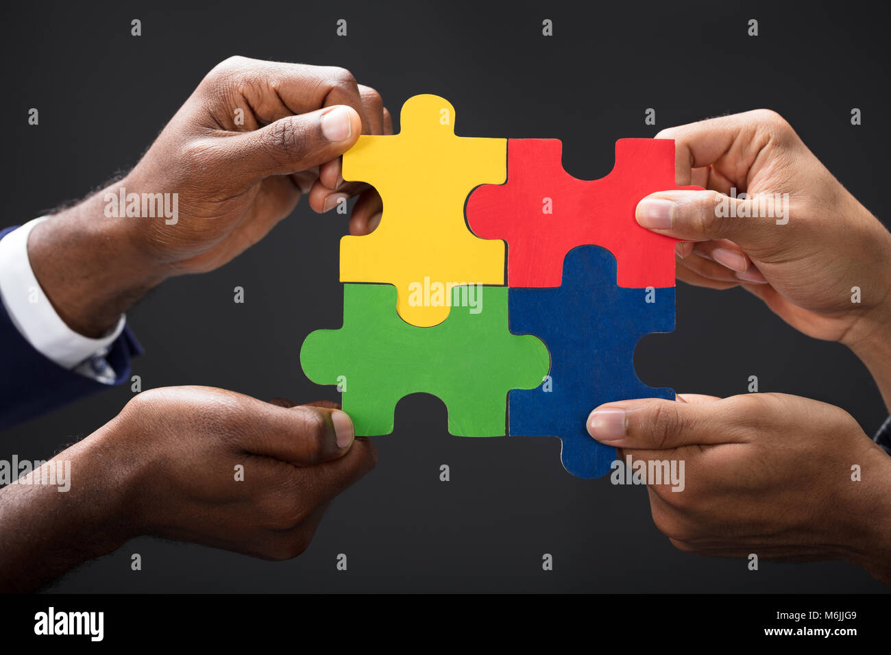 Close-up Of Business Partners Combining Puzzle Pieces On Black ...