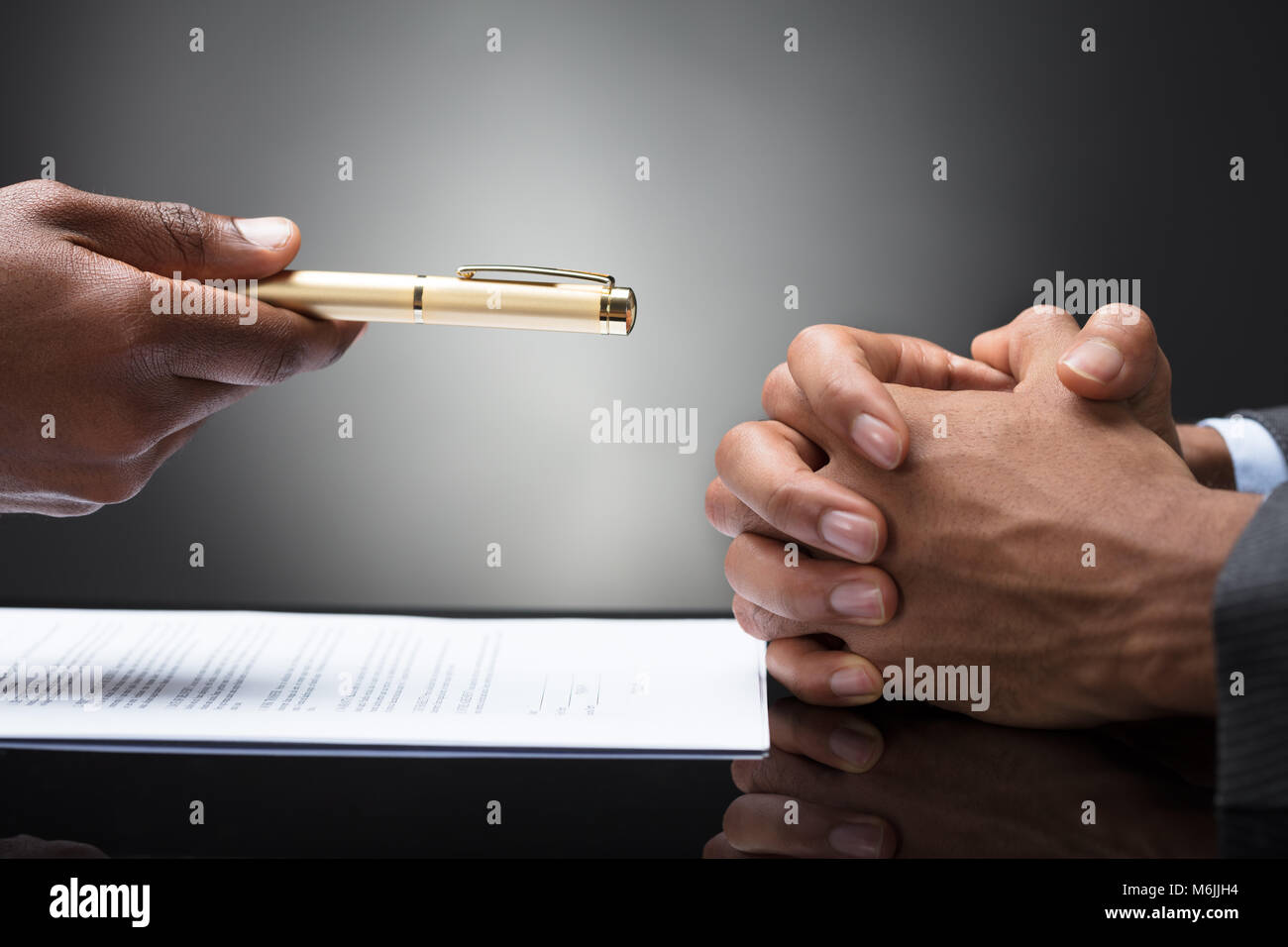 Person Offering Pen To The Other Person With Clasped Hands On Desk ...