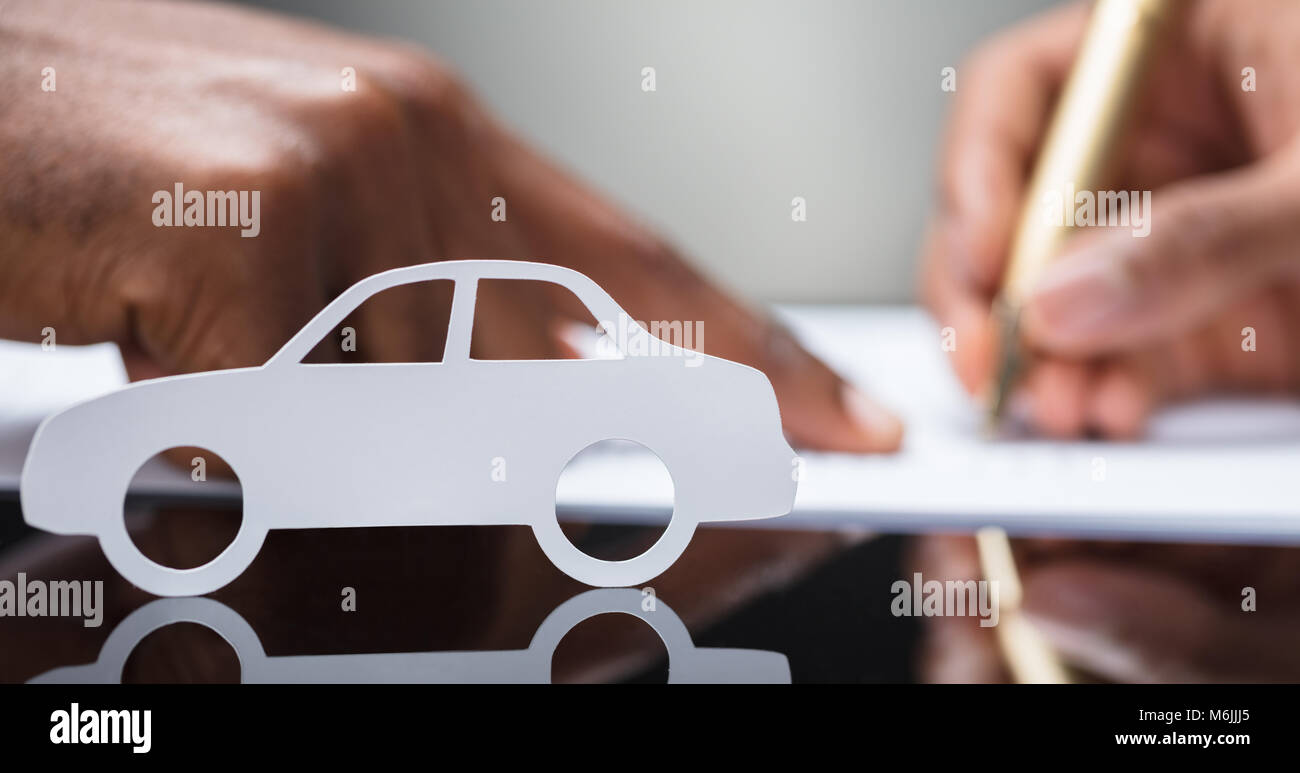 A Person's Hand Signing Car Loan Agreement Contract With Car Silhouette ...