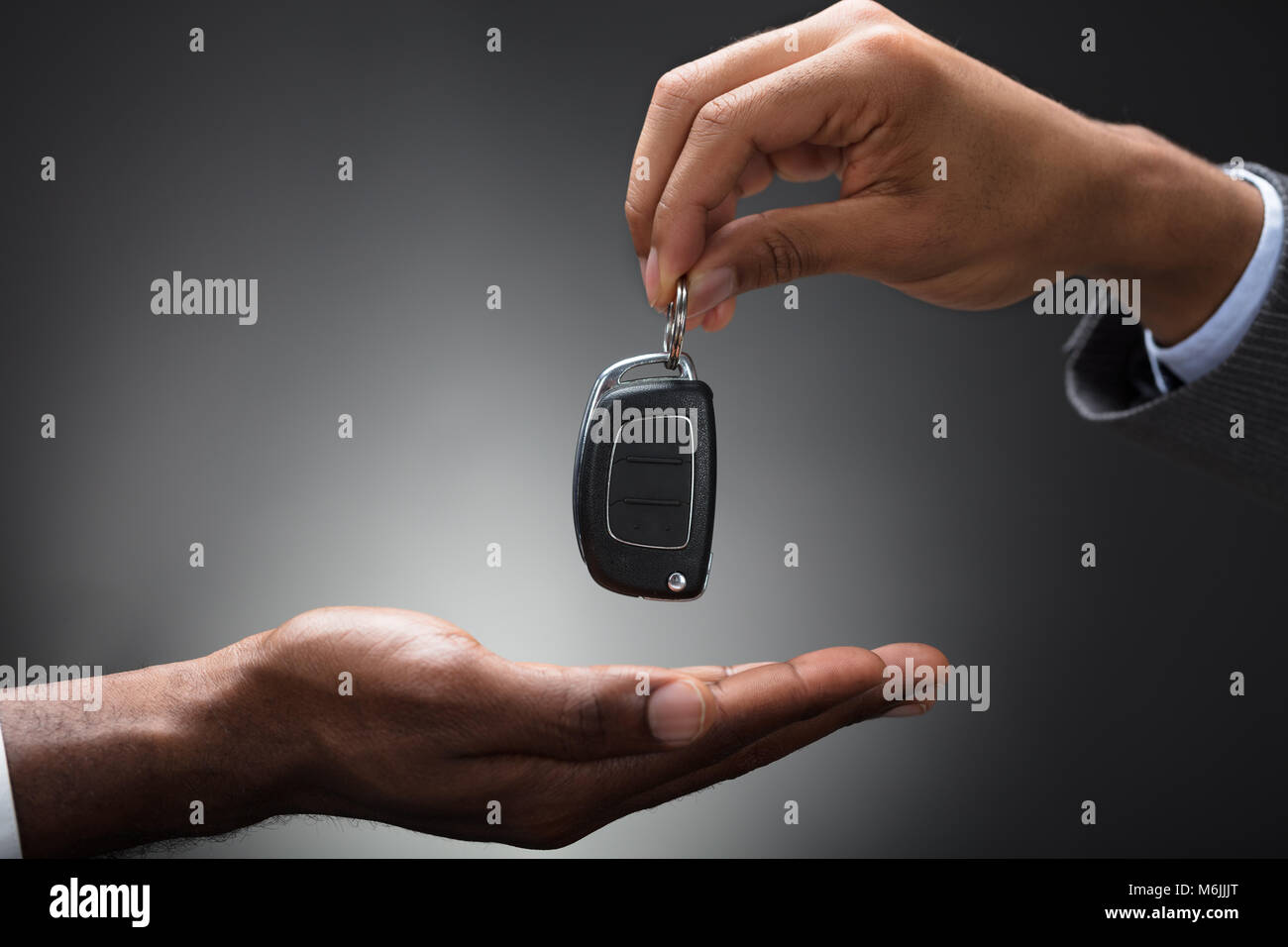 Close-up Of Hand Handing Car Key To The Person Against Gray Background ...