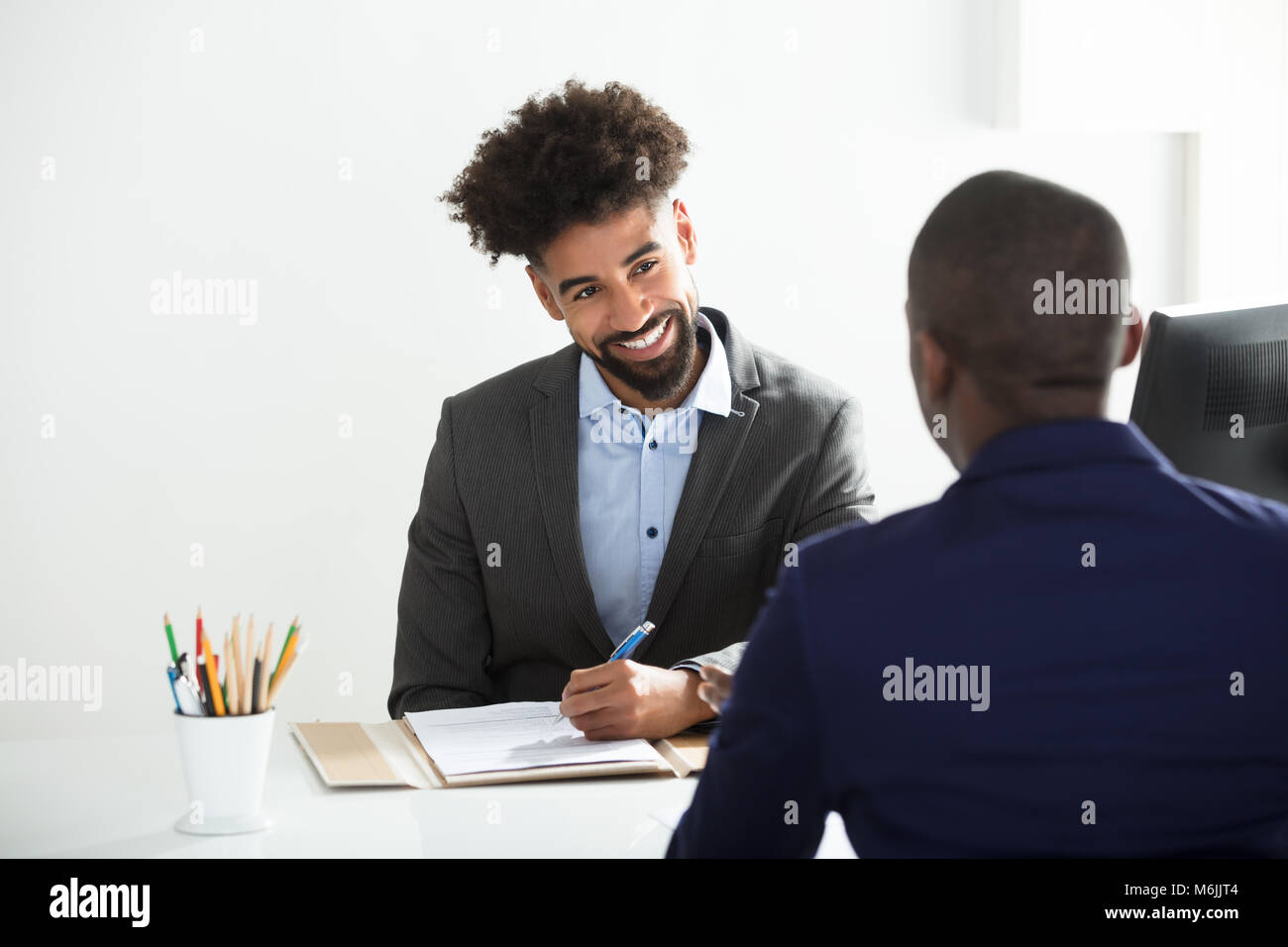 Young Businessman Interviewing Male Candidate In Office Stock Photo - Alamy