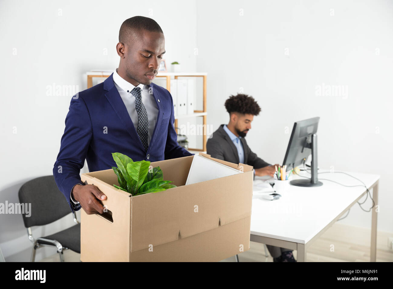 Businessman Moving Out With Cardboard Box From Office With Employee ...