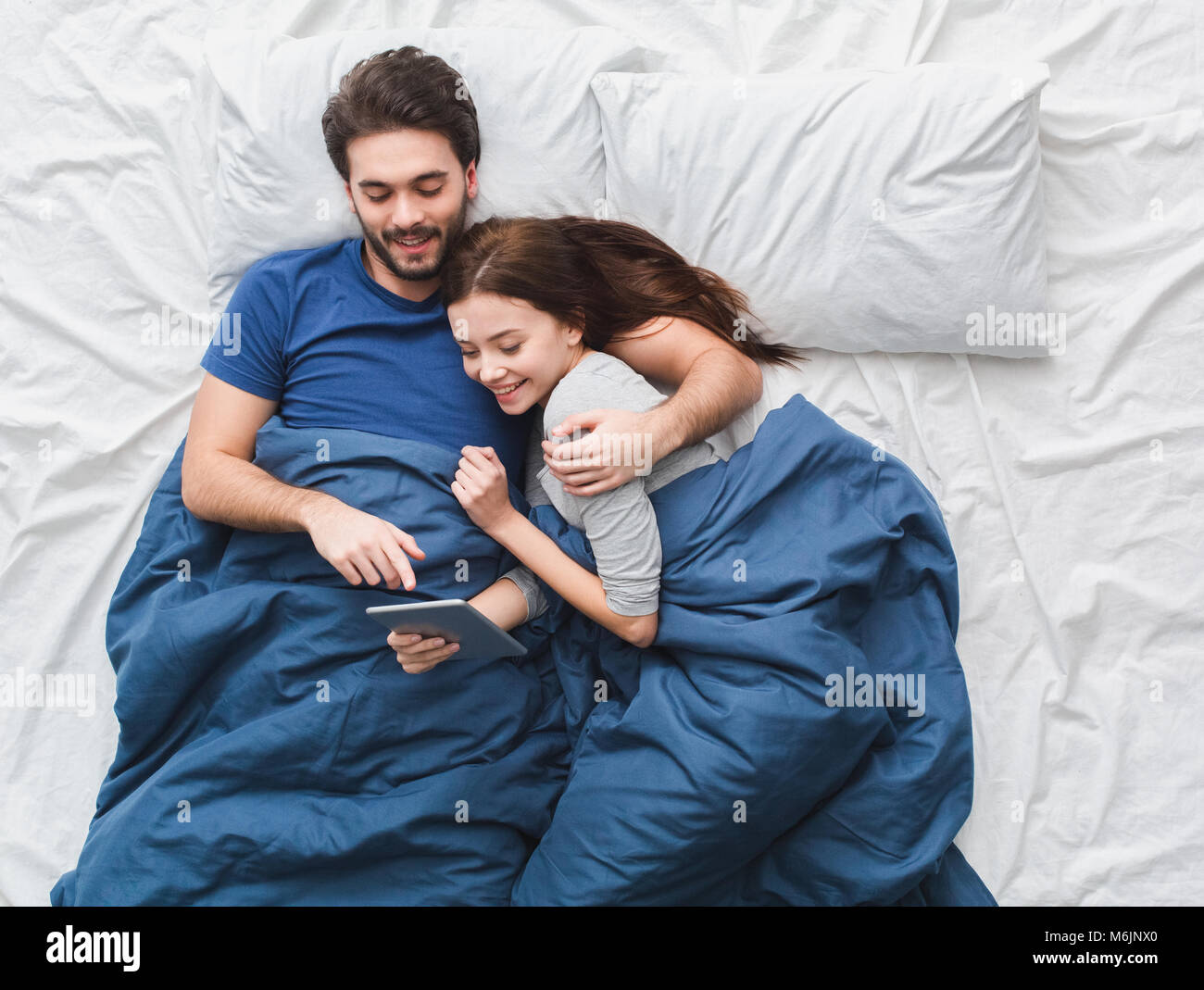 Young couple in bed top view morning concept watching movie on digital ...