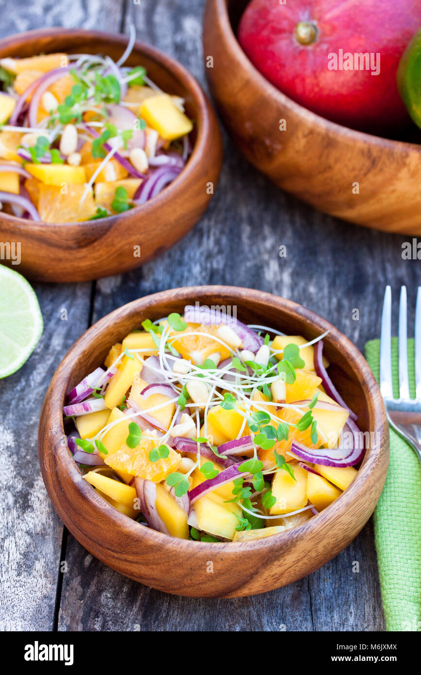 vegetarian salad with mango oranges and red onion in the wooden plate ...
