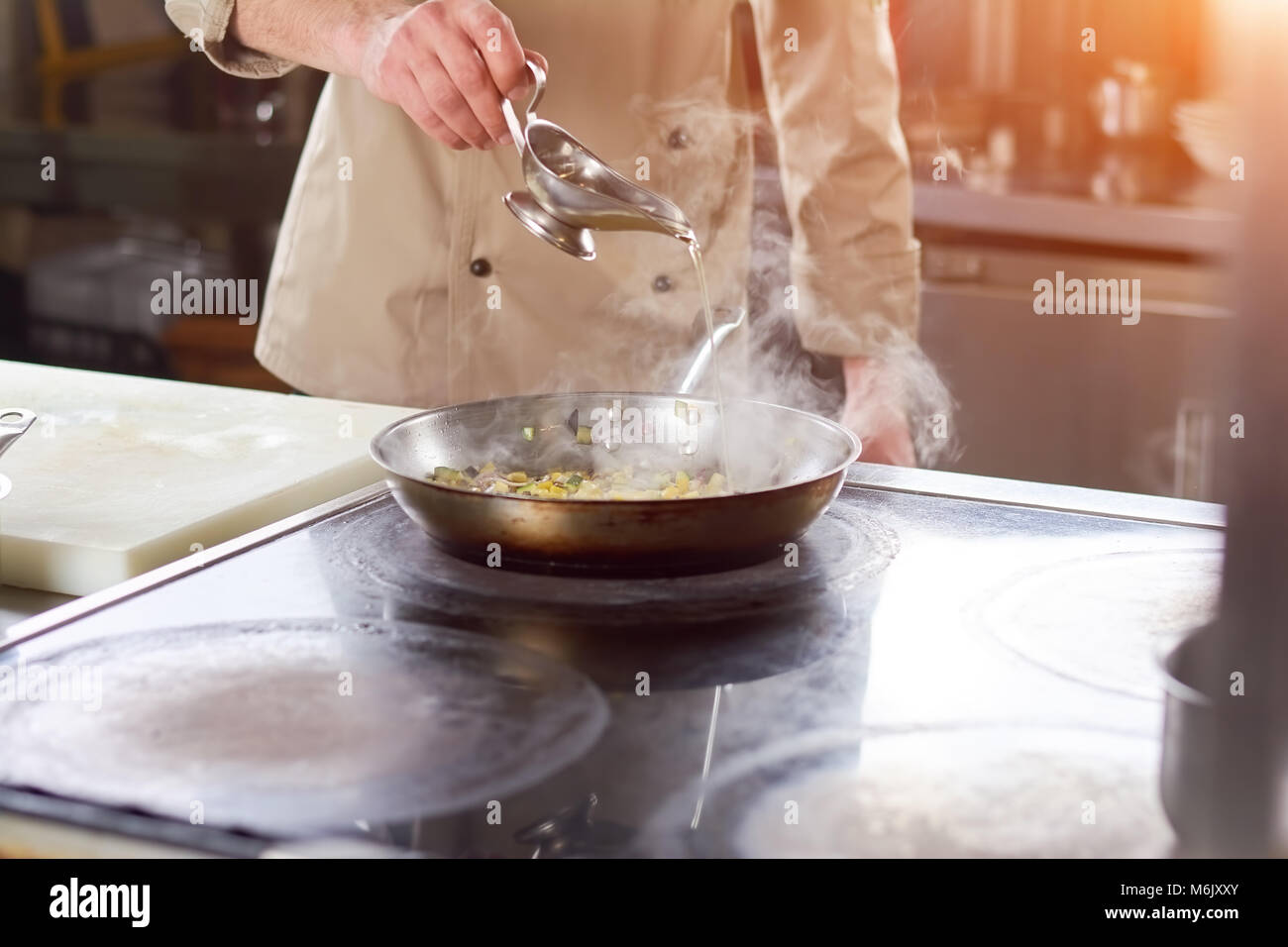 Chef pouring oil into frying pan with vegetables Stock Photo - Alamy