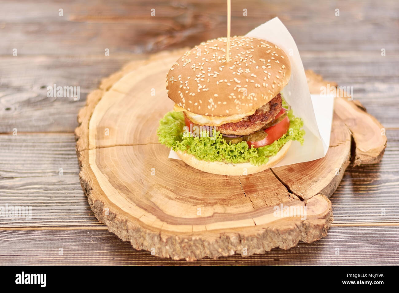 Big tasty burger on round wood Stock Photo - Alamy