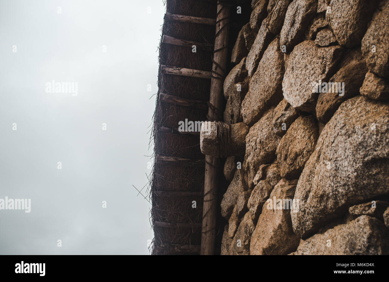 Perfectly preserved ancient stone Inca house with straw roof on a misty ...
