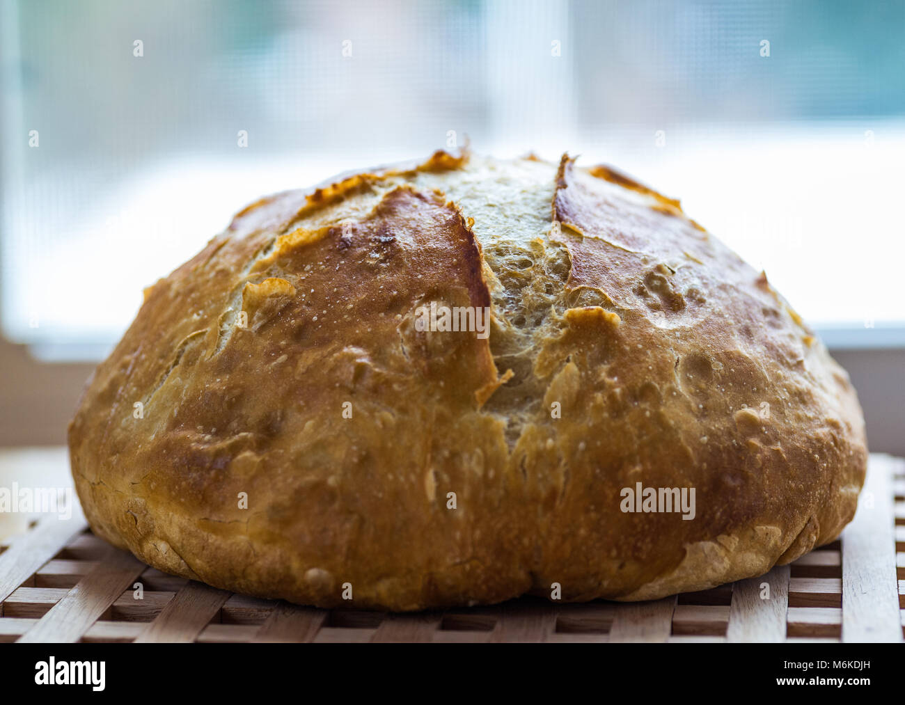horizontal image of a round rustic loaf of bread just out of the oven ...