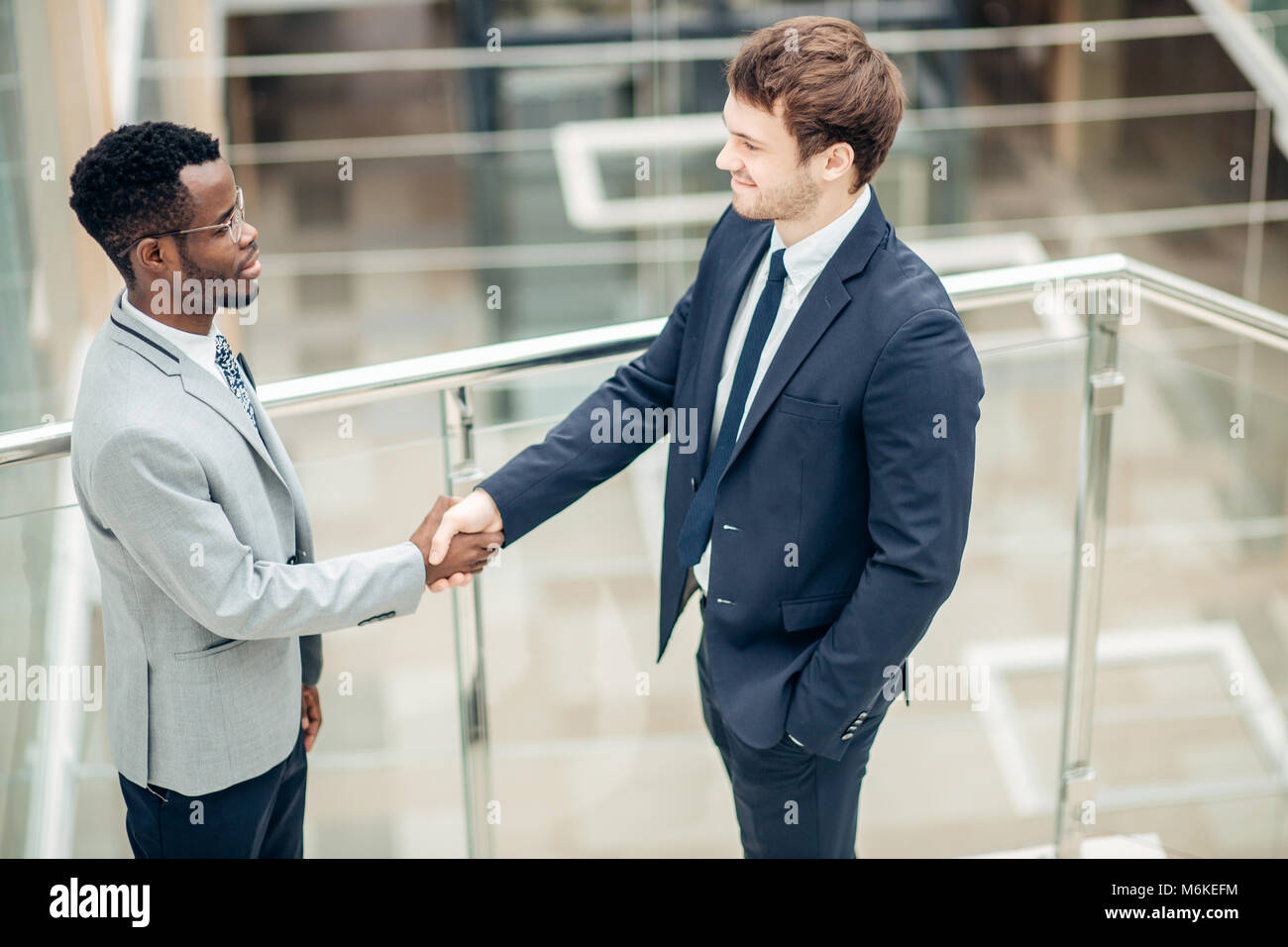 two multiracial businessmen handshaking in modern office for end of ...
