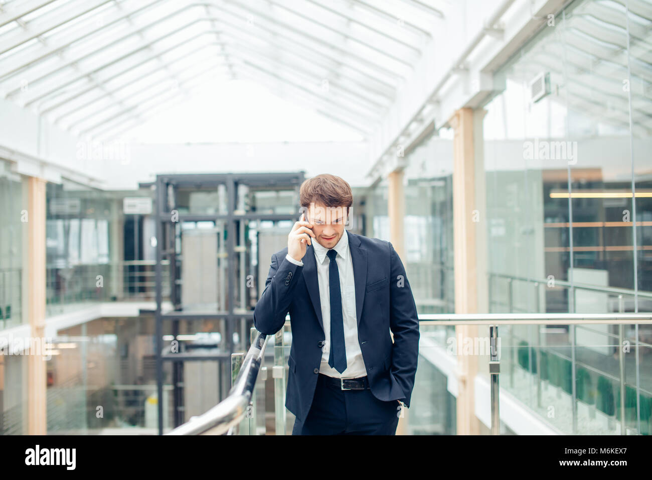 Business man walking while talking on mobile phone on his way to work ...
