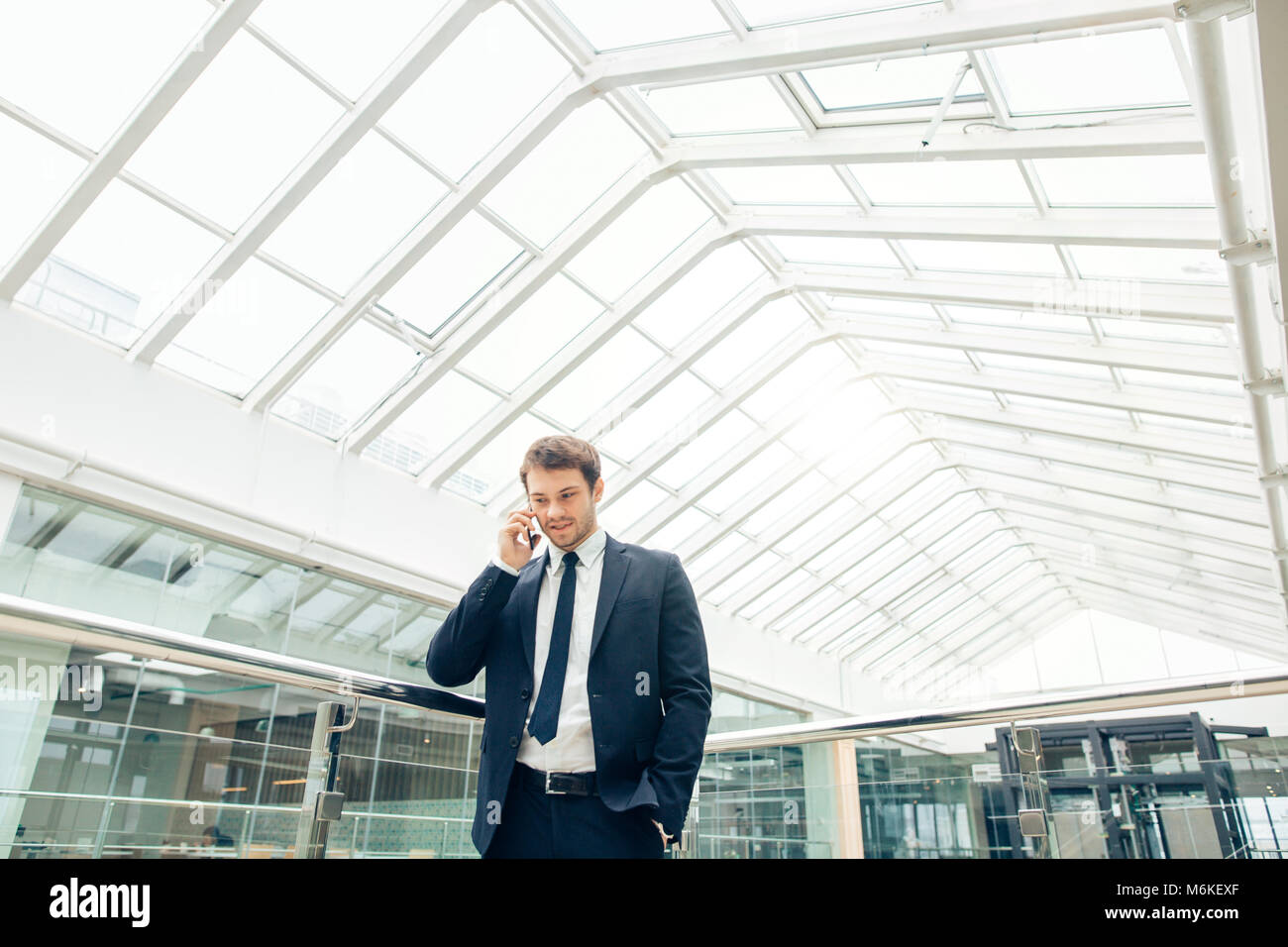 Business man walking while talking on mobile phone on his way to work ...