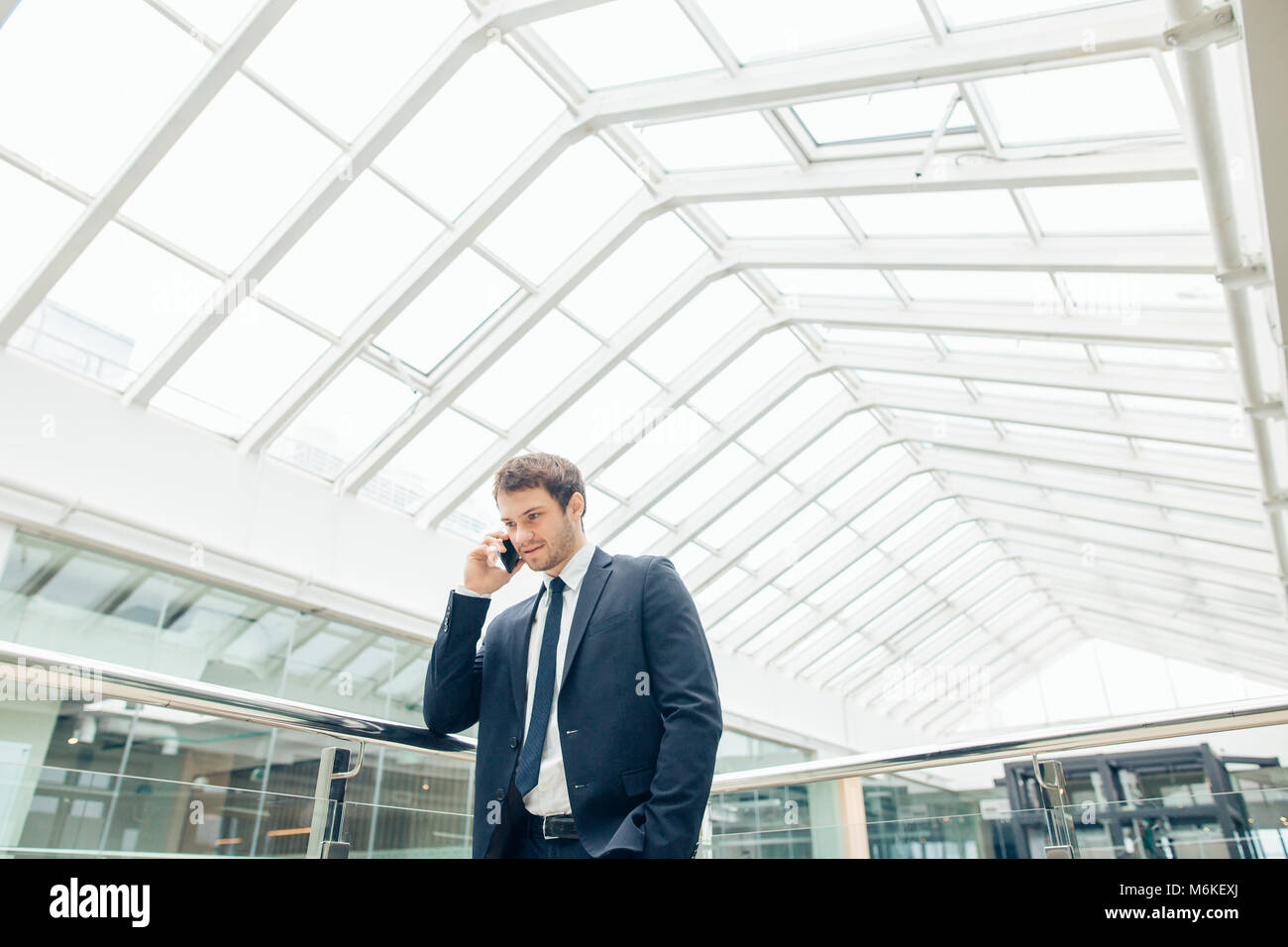 Business man walking while talking on mobile phone on his way to work ...