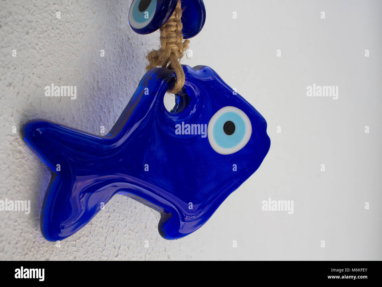 Close up view of an evil eye in shape of fish with white background ...
