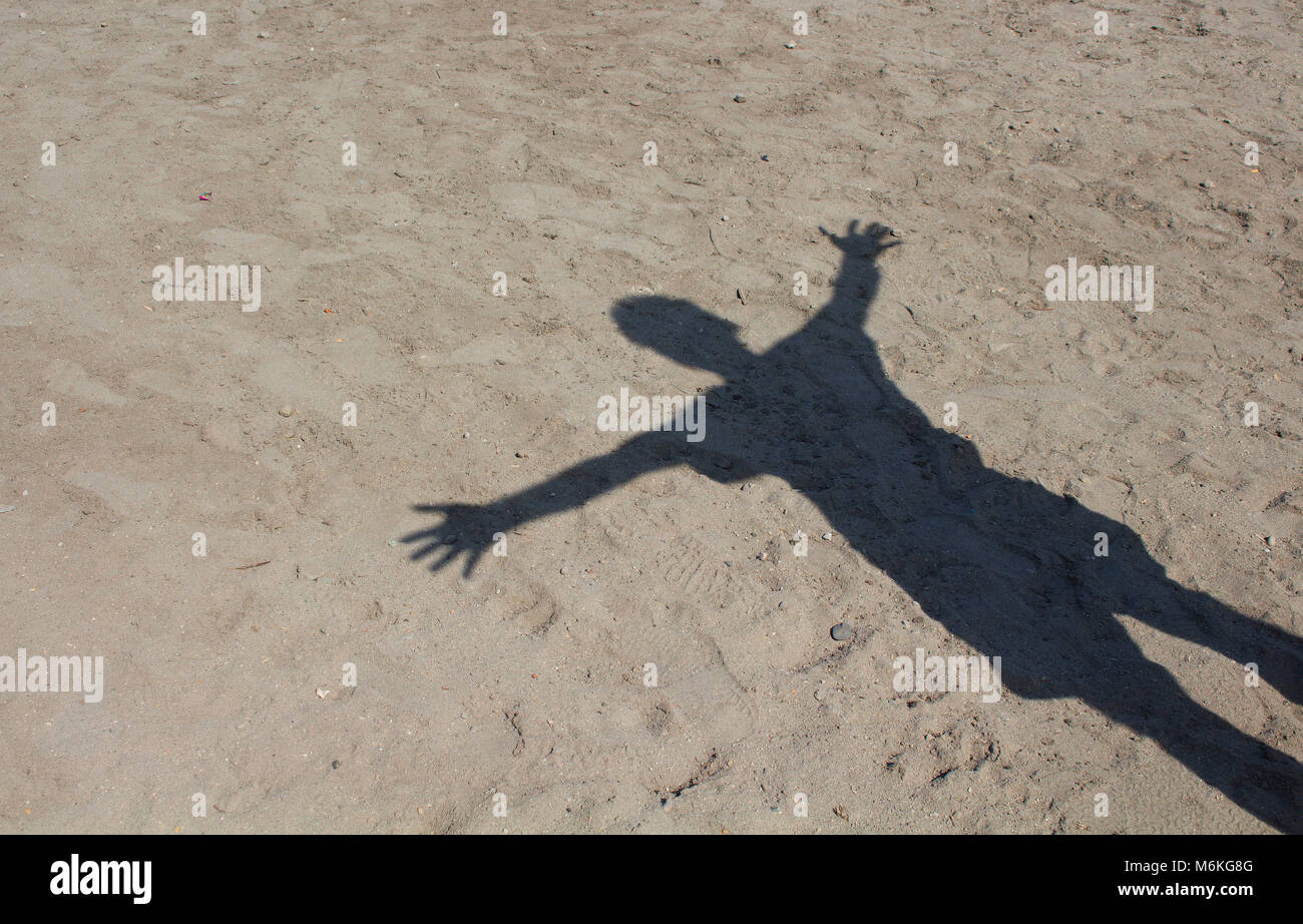 Shadow of man with open arms on sand background Stock Photo - Alamy