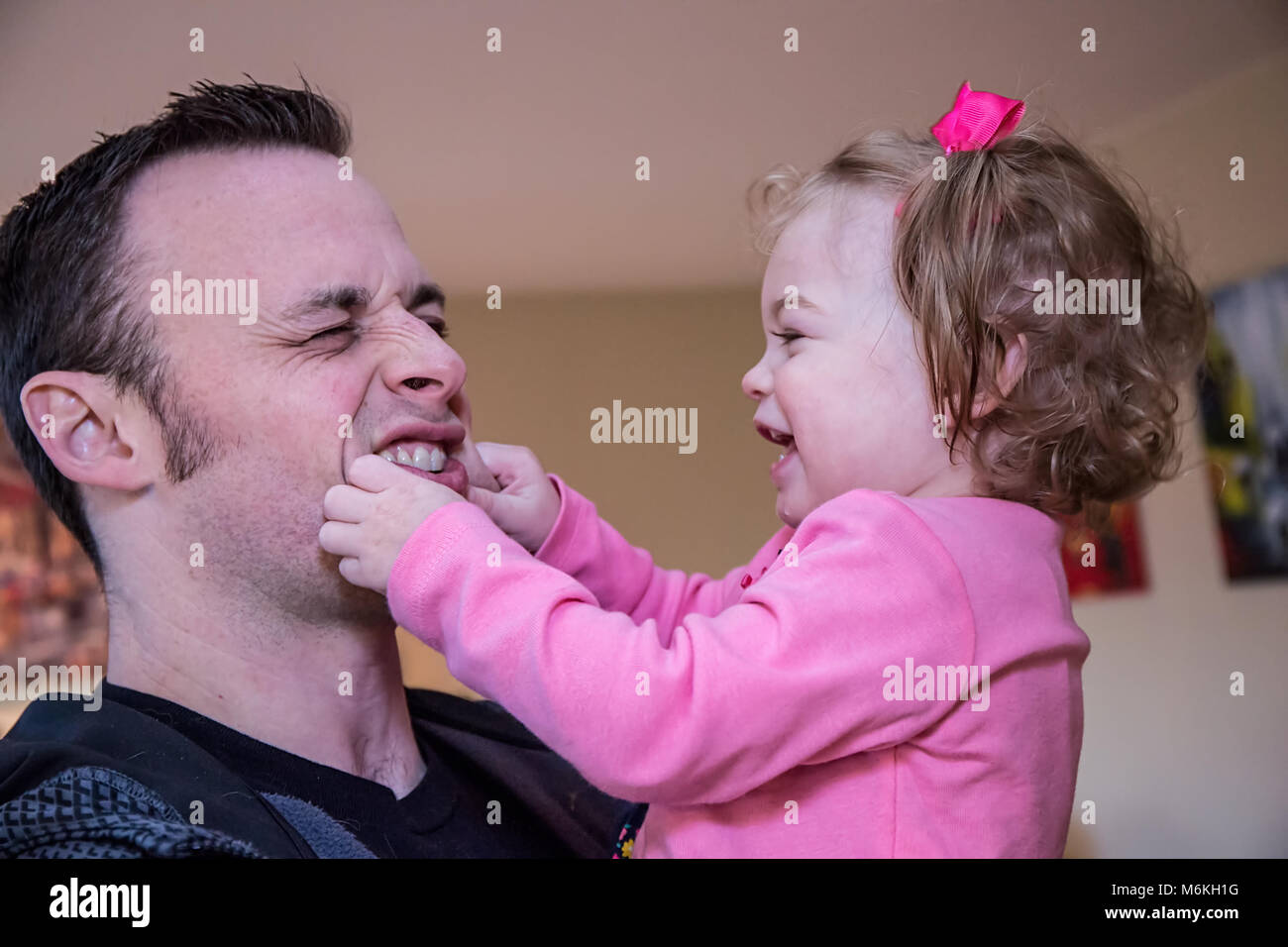 One year old girl having fun pinching her dad's cheeks Stock Photo - Alamy