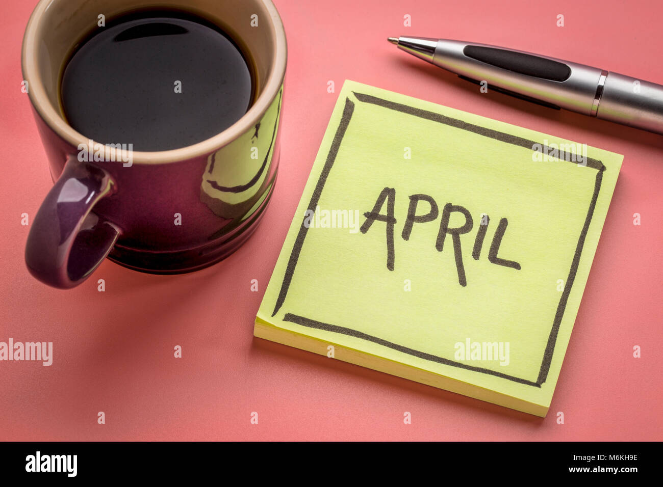 April - handwriting in black ink on a sticky note with a cup of coffee ...