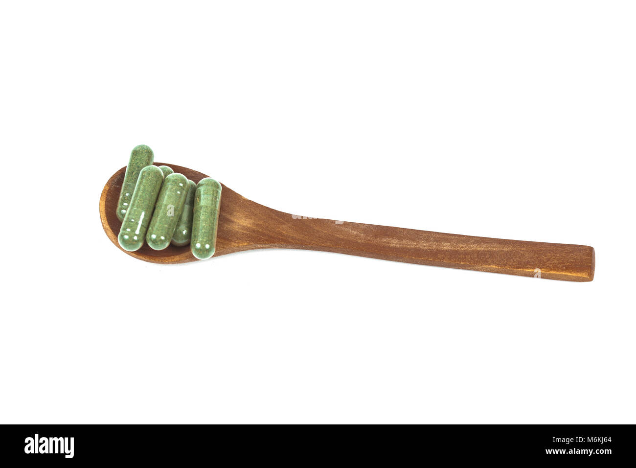 Herbal medicine capsules in wood spoon on white background Stock Photo ...