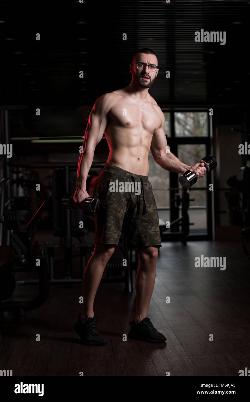 Handsome Man Wearing Glasses Working Out Biceps In A Dark Gym ...