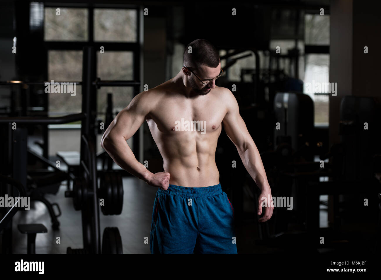 Handsome Geek Man Standing Strong In The Gym And Flexing Muscles ...