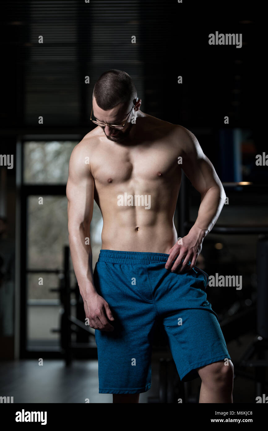 Handsome Geek Man Standing Strong In The Gym And Flexing Muscles ...
