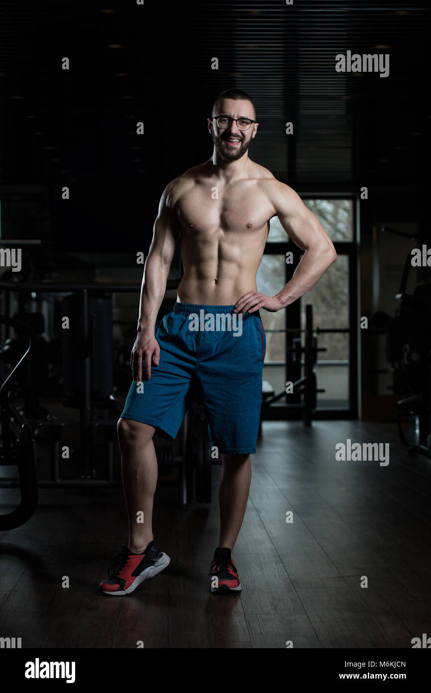 Handsome Geek Man Standing Strong In The Gym And Flexing Muscles ...