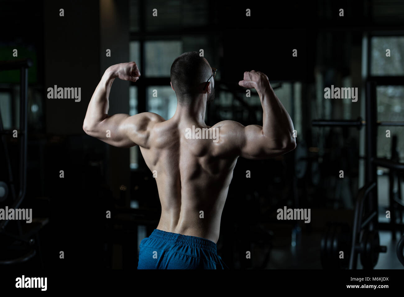 Handsome Geek Man Standing Strong In The Gym And Flexing Muscles ...