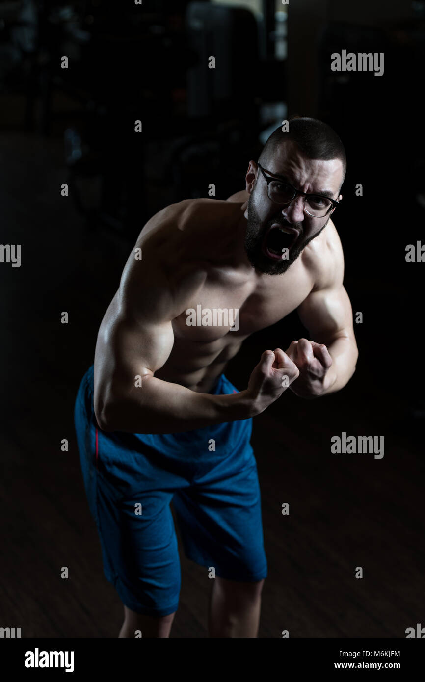 Handsome Geek Man Standing Strong In The Gym And Flexing Muscles ...