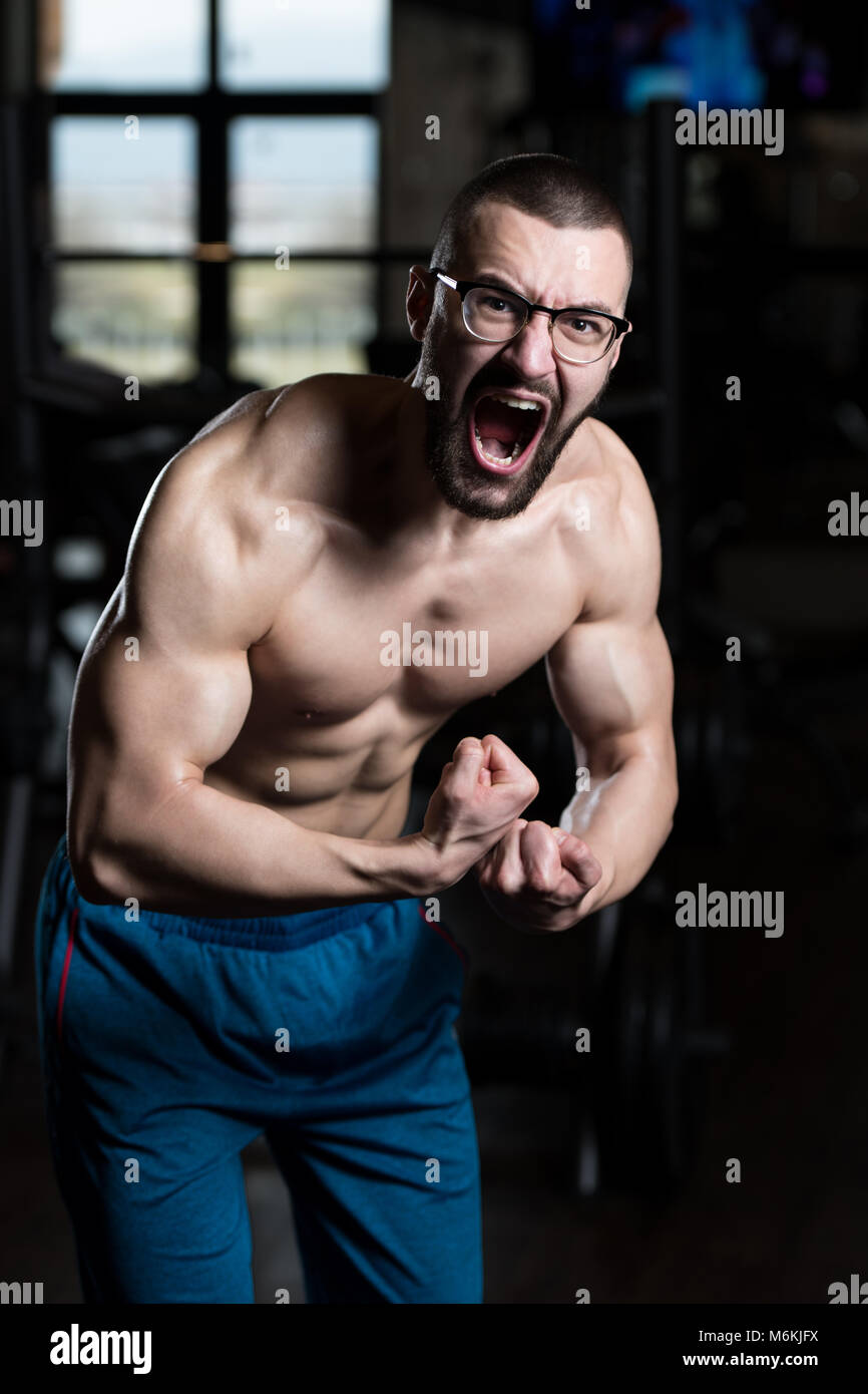 Handsome Geek Man Standing Strong In The Gym And Flexing Muscles ...