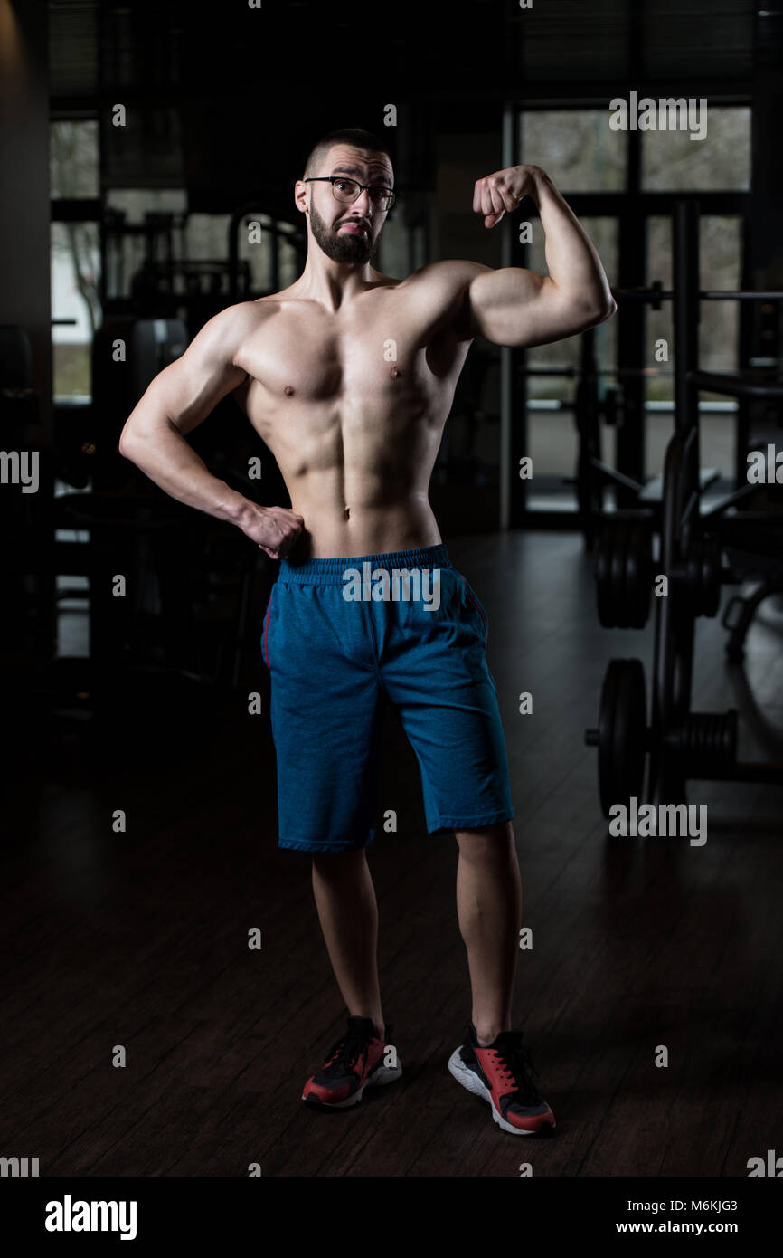 Handsome Geek Man Standing Strong In The Gym And Flexing Muscles ...