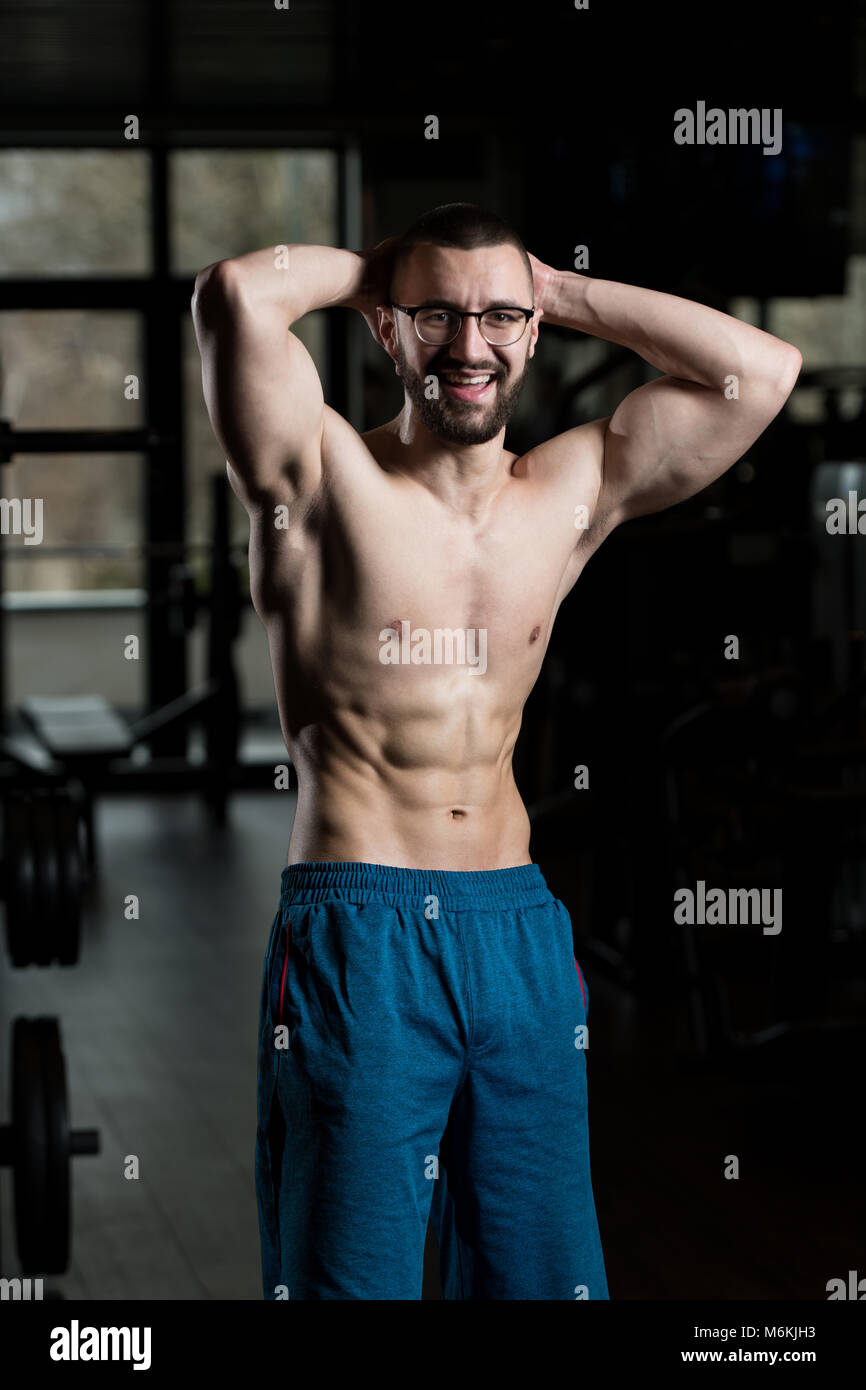 Handsome Geek Man Standing Strong In The Gym And Flexing Muscles ...