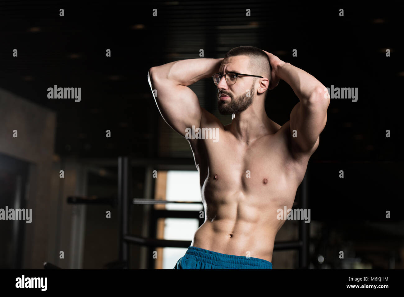 Handsome Geek Man Standing Strong In The Gym And Flexing Muscles ...