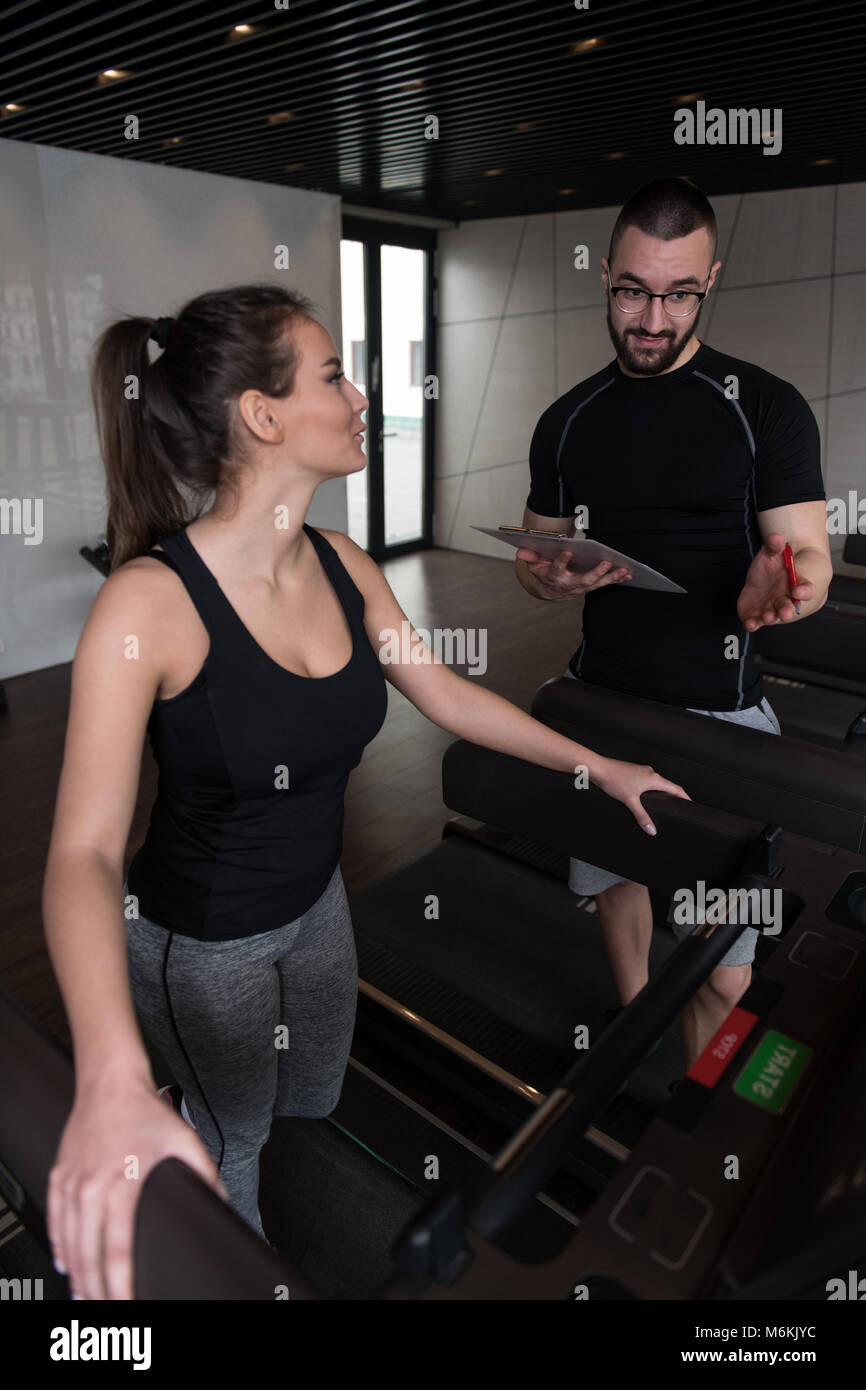 Personal Trainer Showing Young Woman How To Train Aerobics Elliptical ...