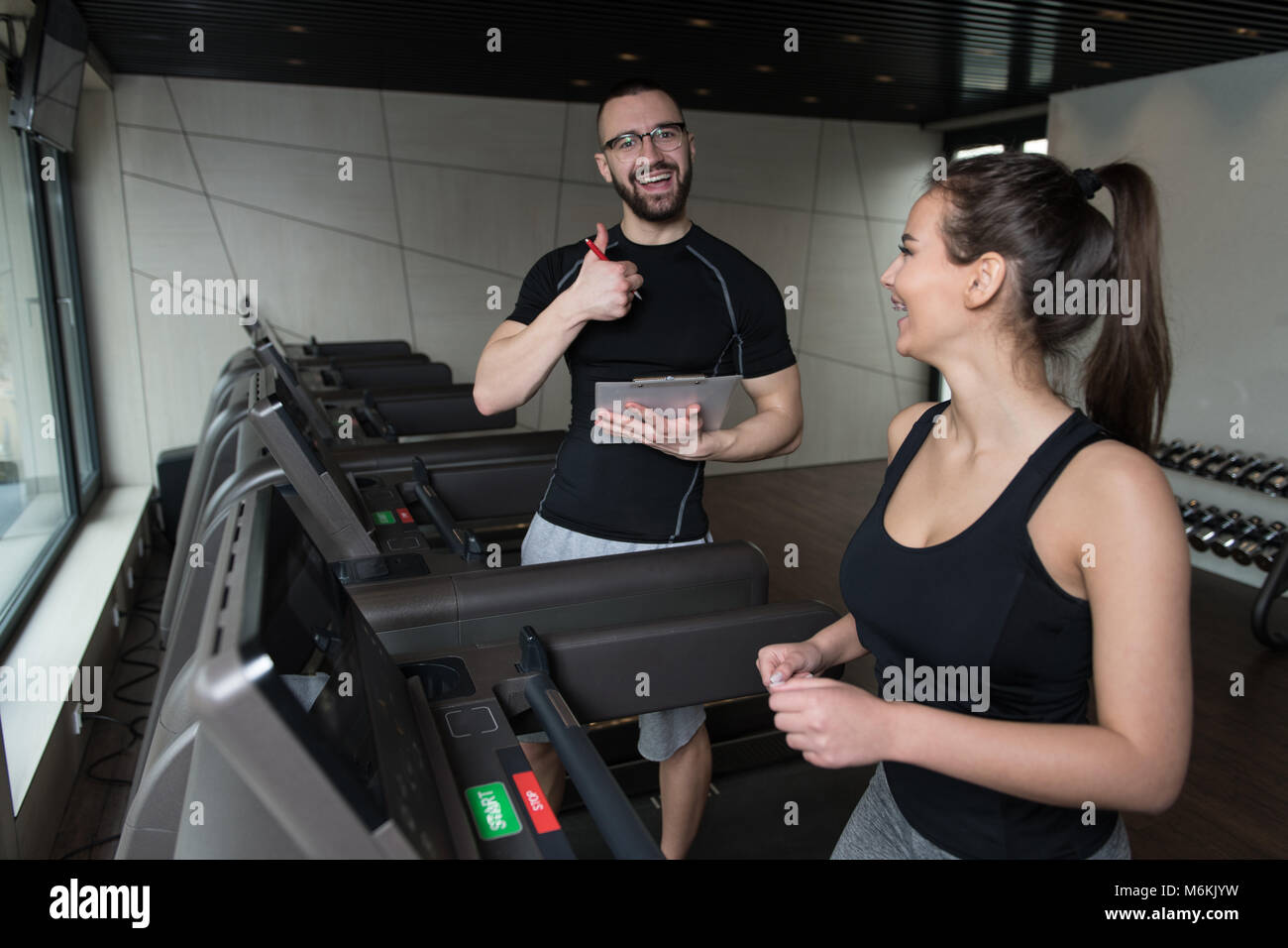 Personal Trainer Showing Young Woman How To Train Aerobics Elliptical ...