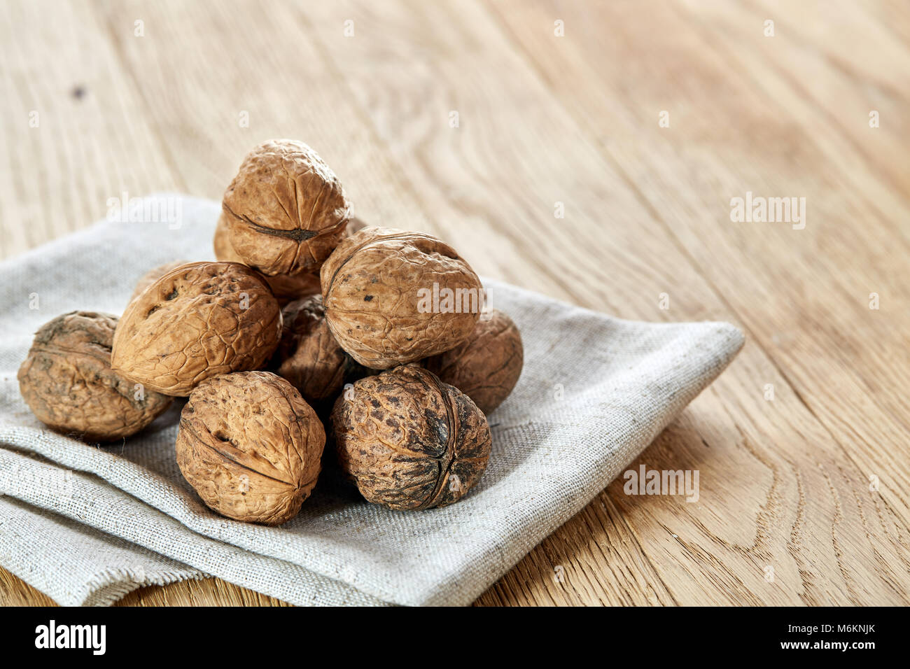 A stack of hard shells of walnuts piled together on light grey fabric ...