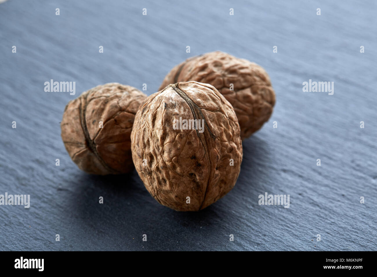 A stack of hard shells of walnuts piled together on dark stony ...