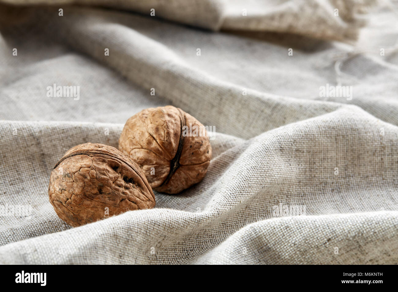 A stack of hard shells of walnuts piled together on light grey fabric ...