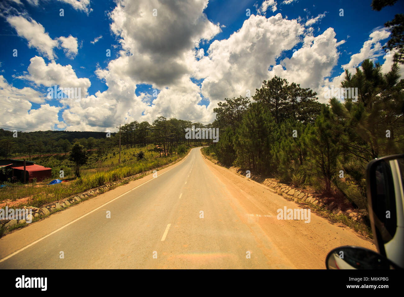 sunny highway vanishes into space among hilly country land against ...