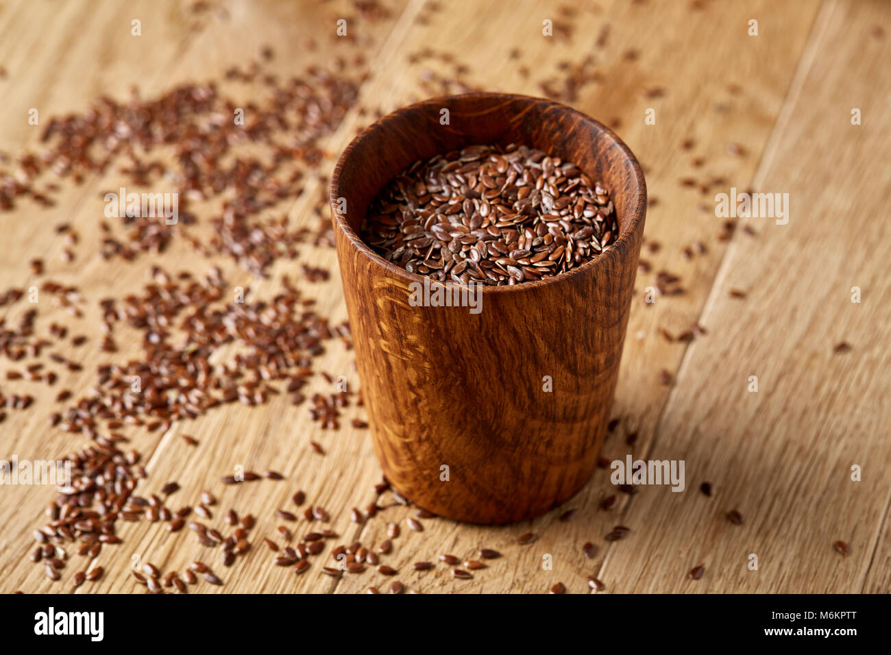 An overturned wooden bowl with linseeds on a brown rustic wooden ...