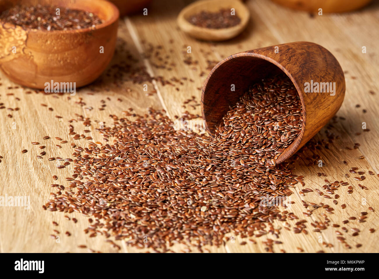 An overturned wooden bowl with linseeds on a brown rustic wooden ...
