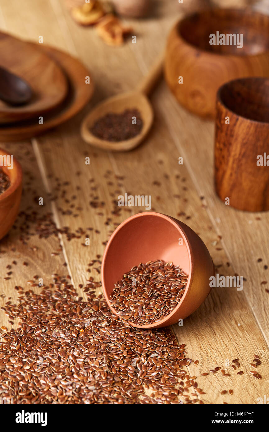 An overturned ceramic clay bowl with linseeds on a brown rustic wooden ...