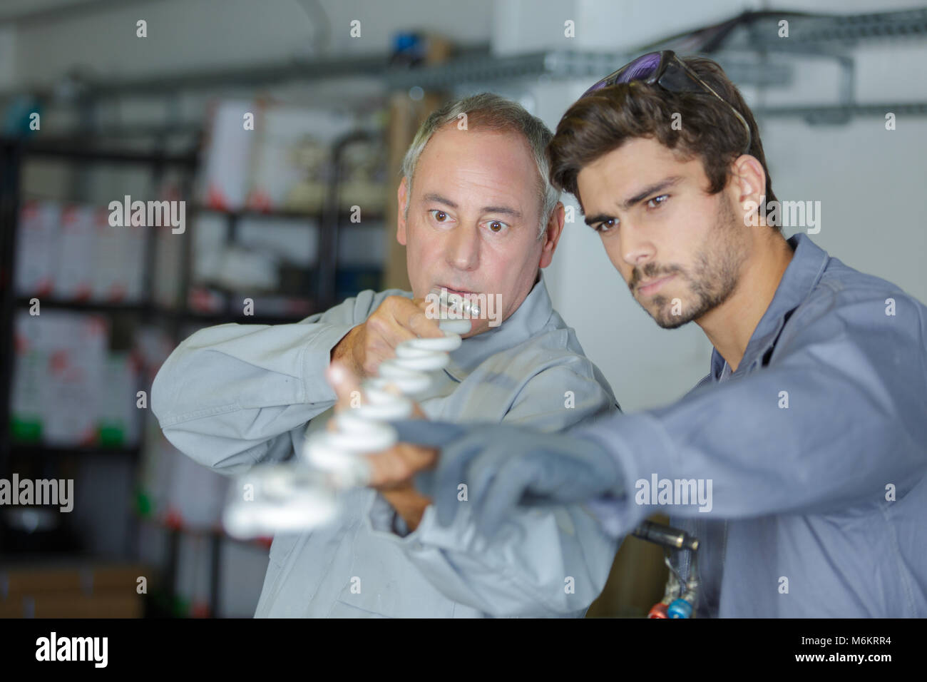 two industrial workers inspecting work piece Stock Photo - Alamy