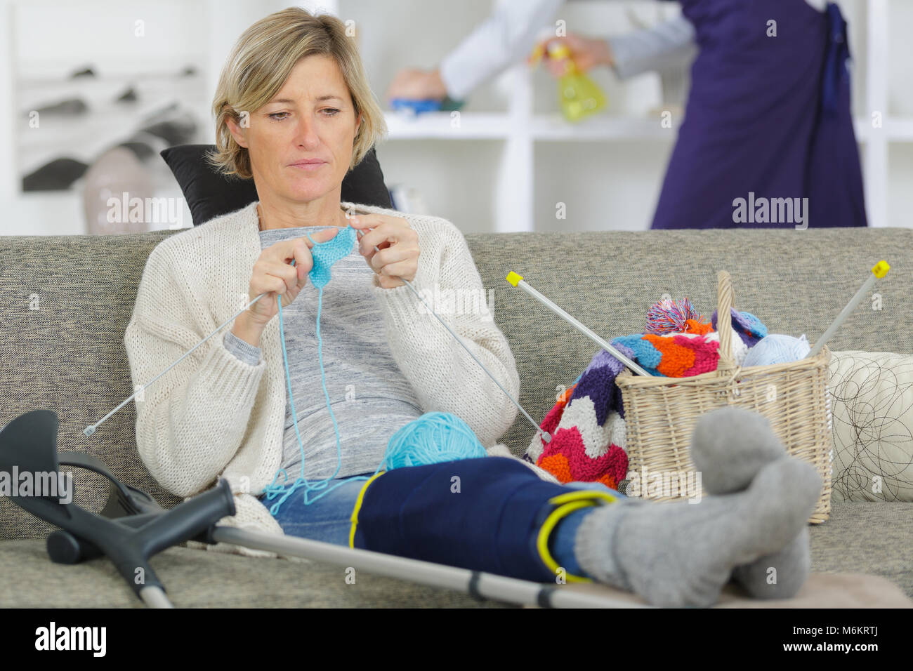 cheerful injured woman knitting on the sofa Stock Photo - Alamy